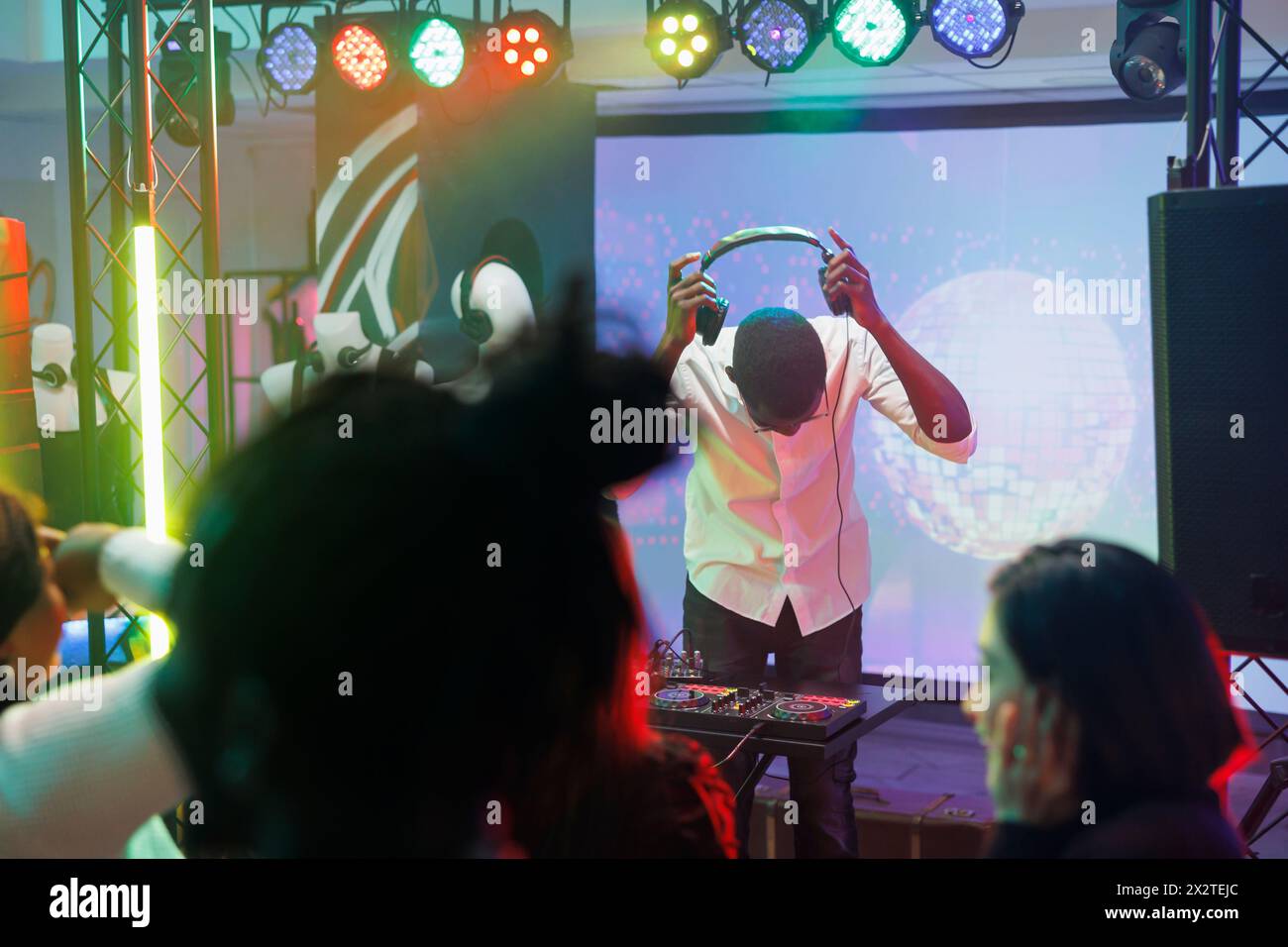Dj wearing headphones on stage with spotlights during concert live ...