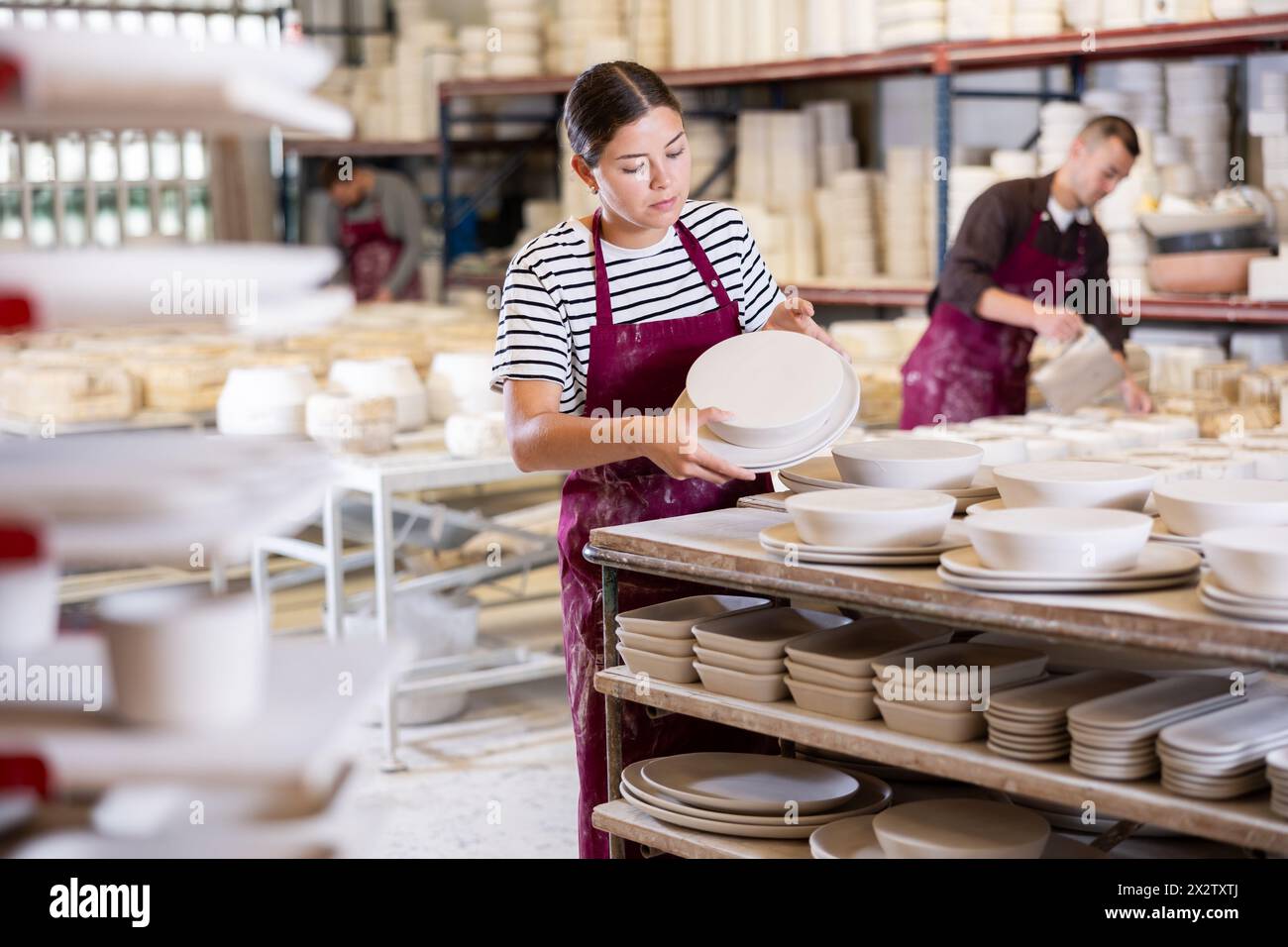 Female ceramicist placing handcrafted plates on storage racks Stock ...