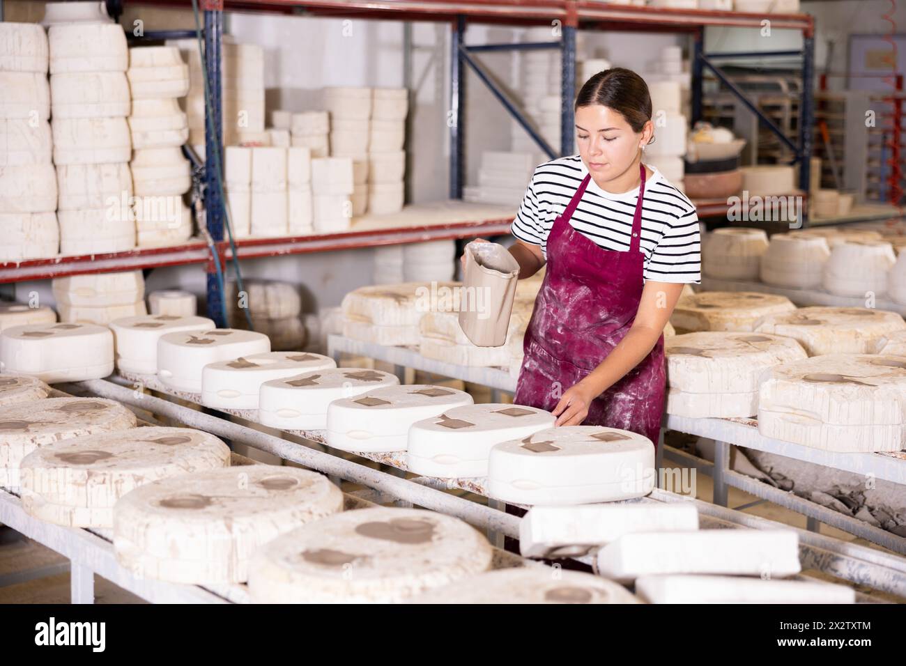 Female ceramicist filling casting molds with slip in pottery workshop ...