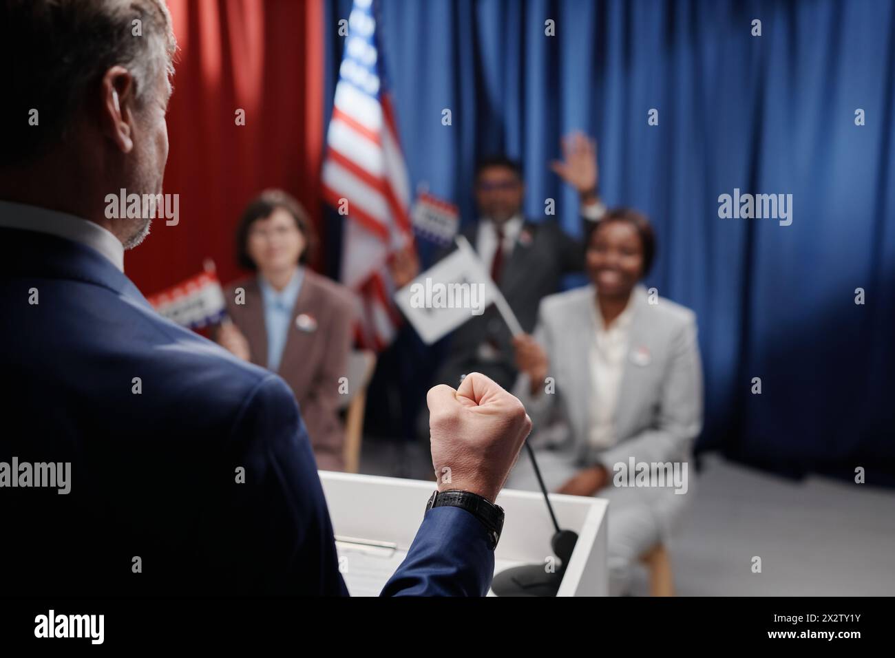 Mature male politician keeping punch over platform with microphone ...