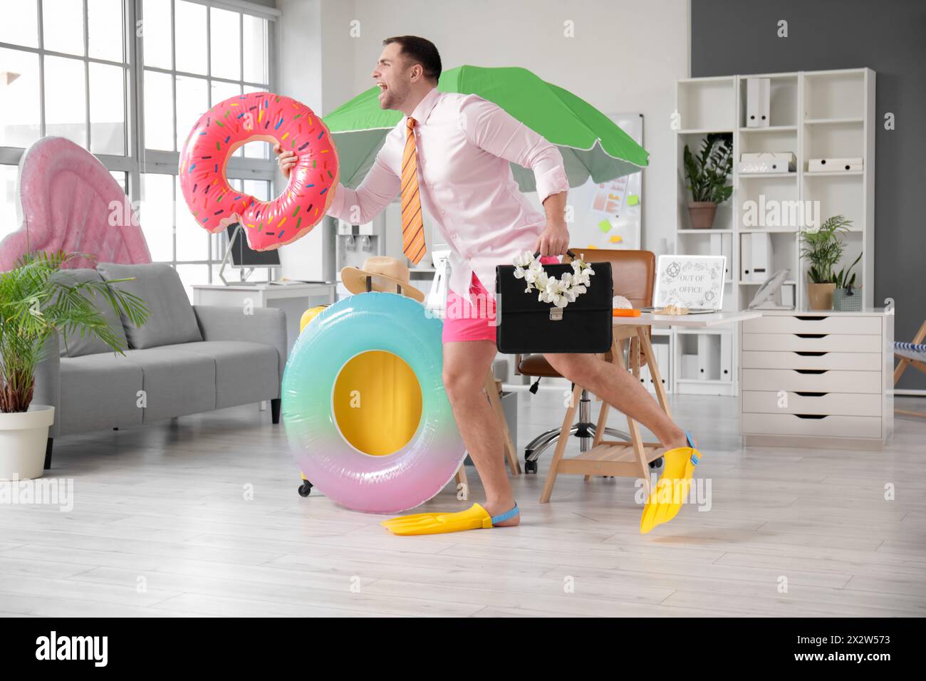 Happy male office worker with suitcase and inflatable rings running in ...