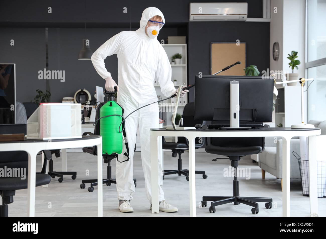 Male worker disinfecting workplace in office Stock Photo - Alamy