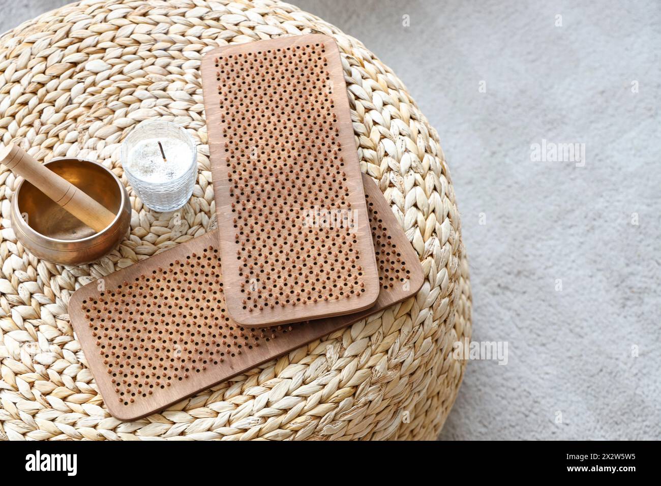 Sadhu board with Tibetan bowl and aroma stick on pouf in room, top view ...