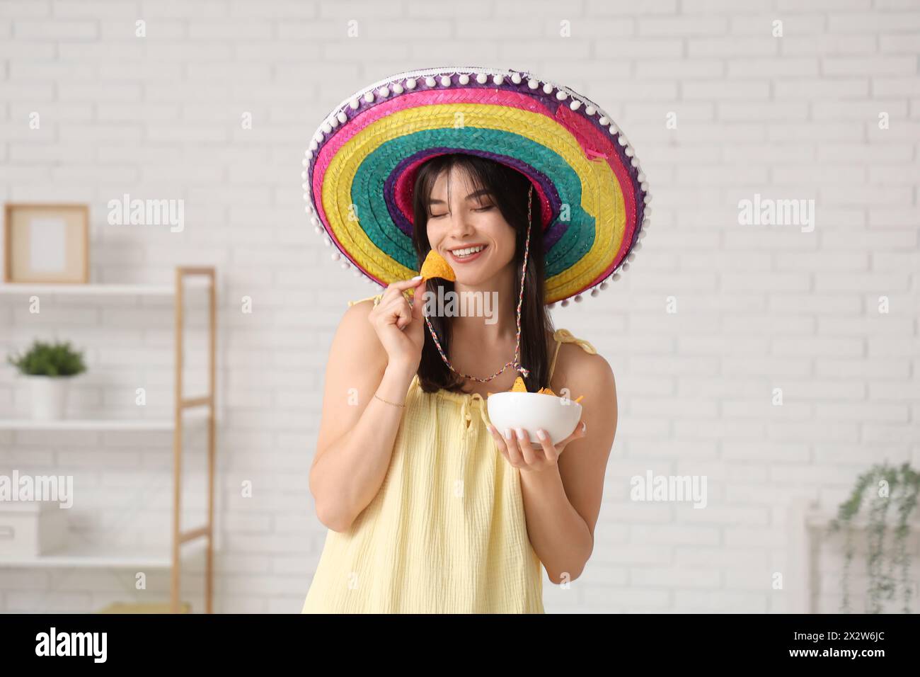 Young woman in sombrero with nachos at home. Cinco de Mayo celebration ...