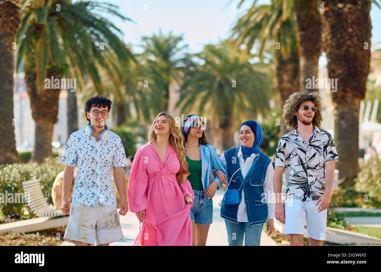 A diverse group of tourists, dressed in summer attire, strolls through ...
