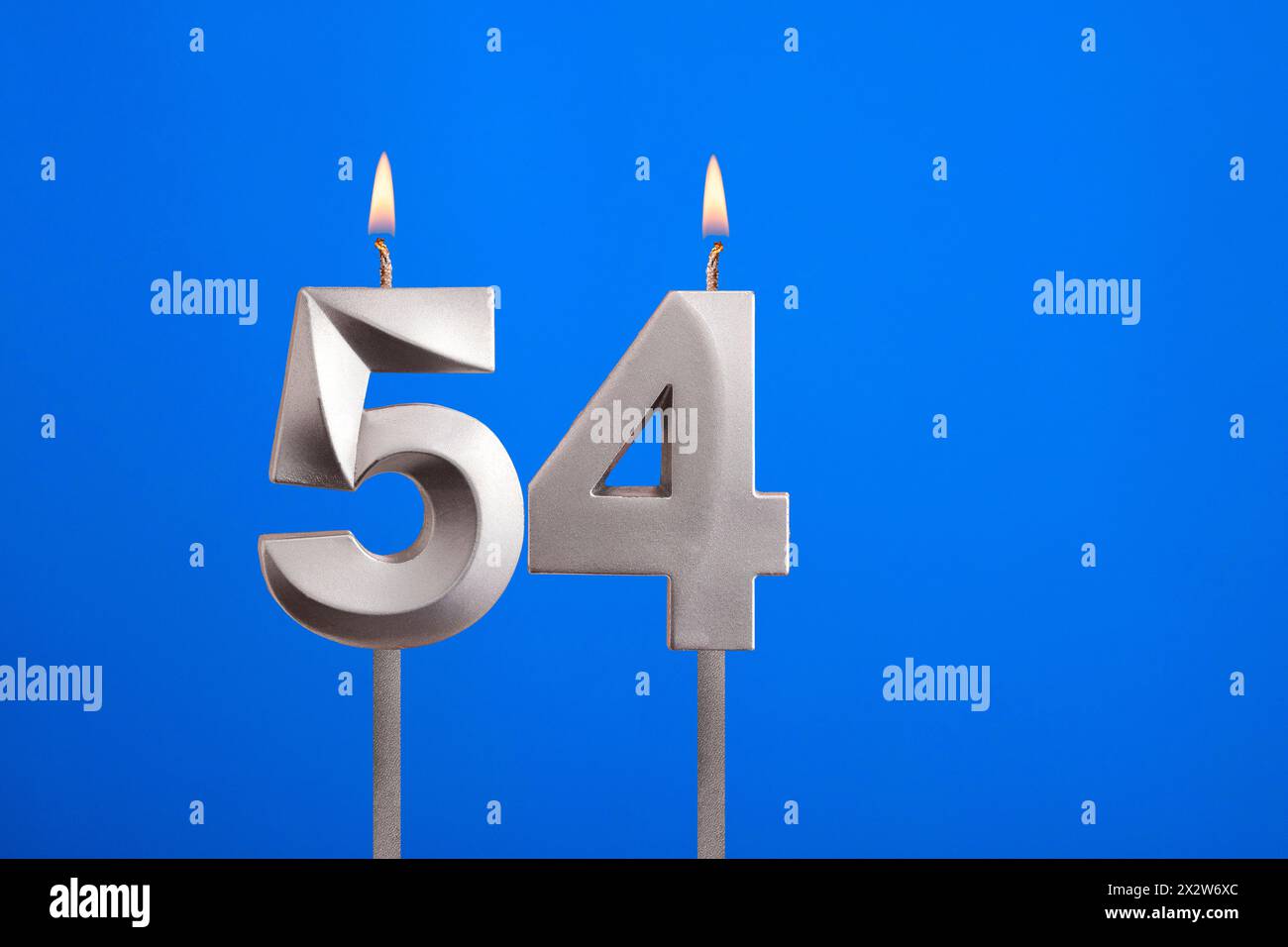 Birthday number 54 - Candle lit on blue background Stock Photo - Alamy