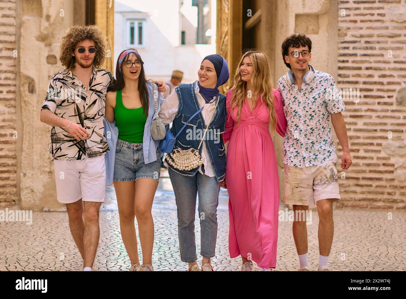 A diverse group of tourists, dressed in summer attire, strolls through ...
