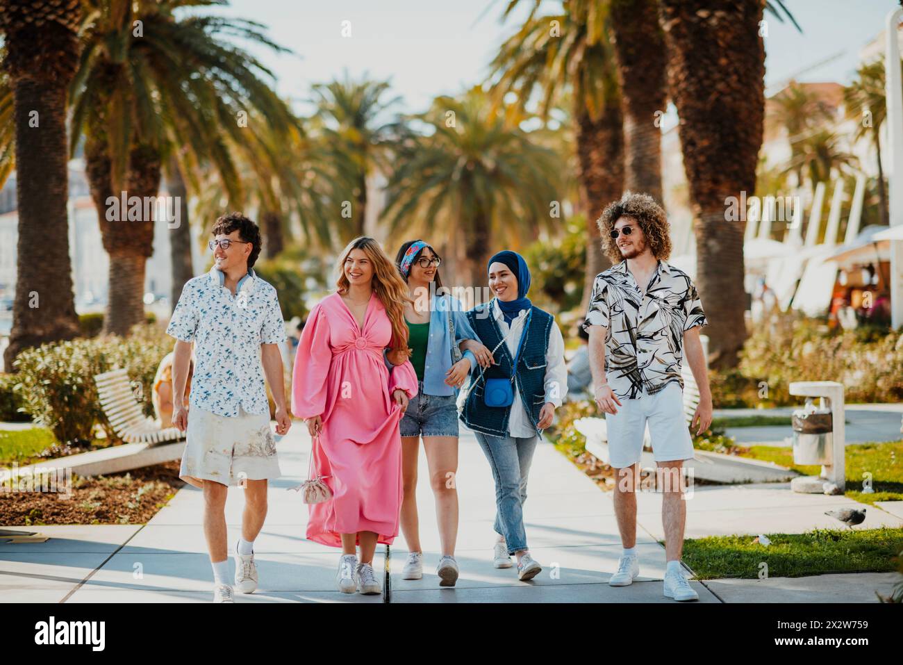 A diverse group of tourists, dressed in summer attire, strolls through ...