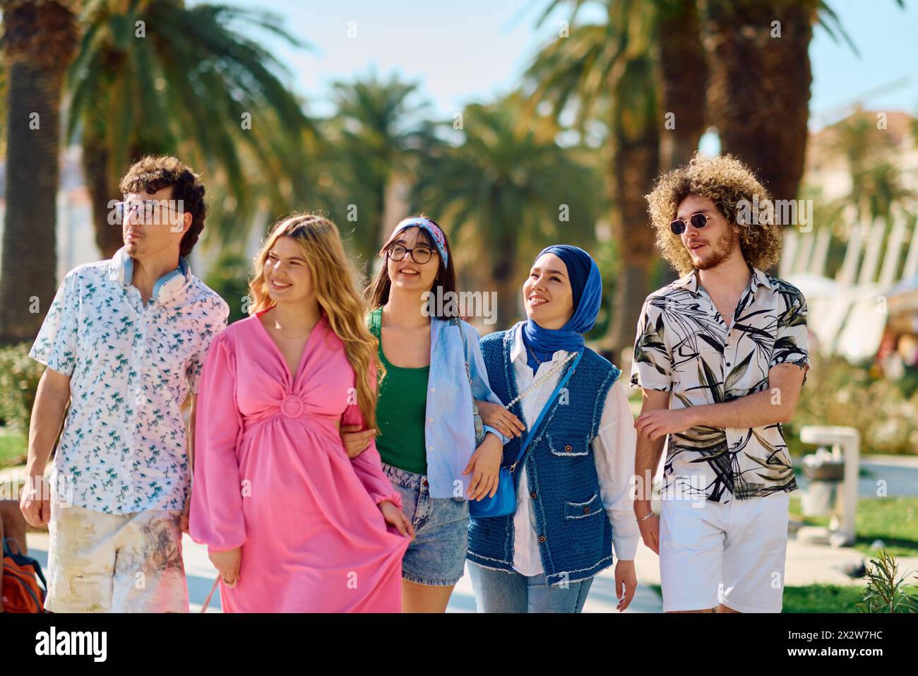 A diverse group of tourists, dressed in summer attire, strolls through ...