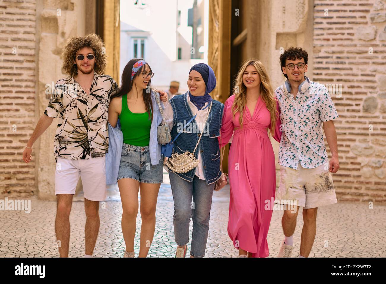 A diverse group of tourists, dressed in summer attire, strolls through ...