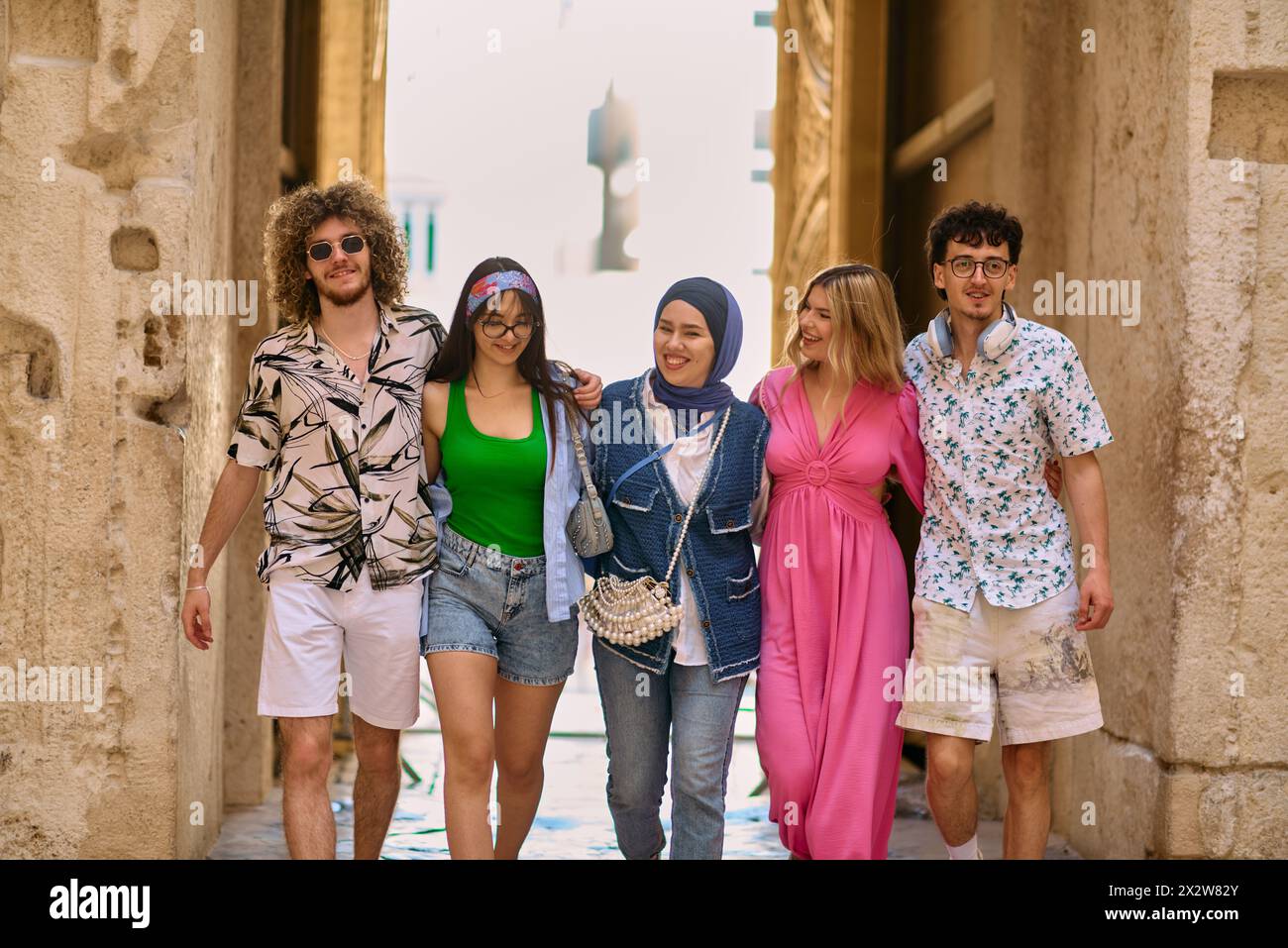 A diverse group of tourists, dressed in summer attire, strolls through ...