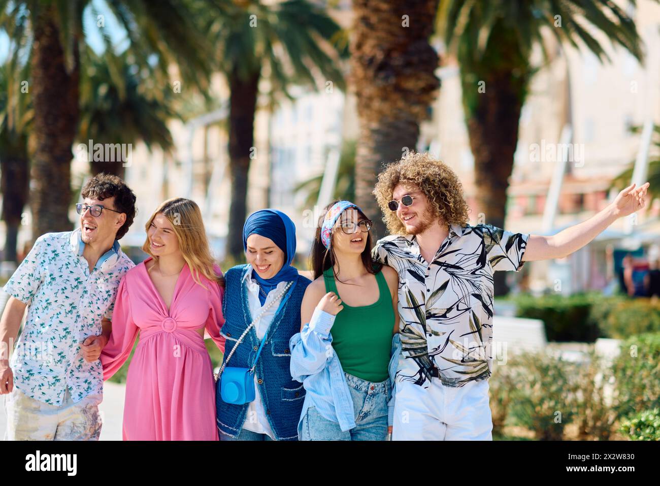 A diverse group of tourists, dressed in summer attire, strolls through ...
