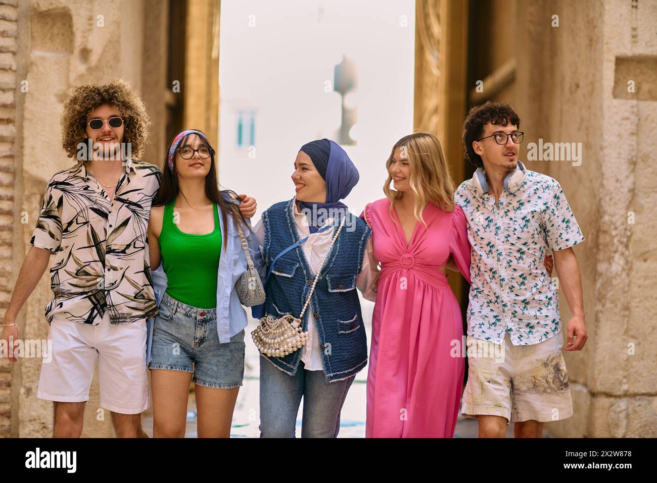 A diverse group of tourists, dressed in summer attire, strolls through ...