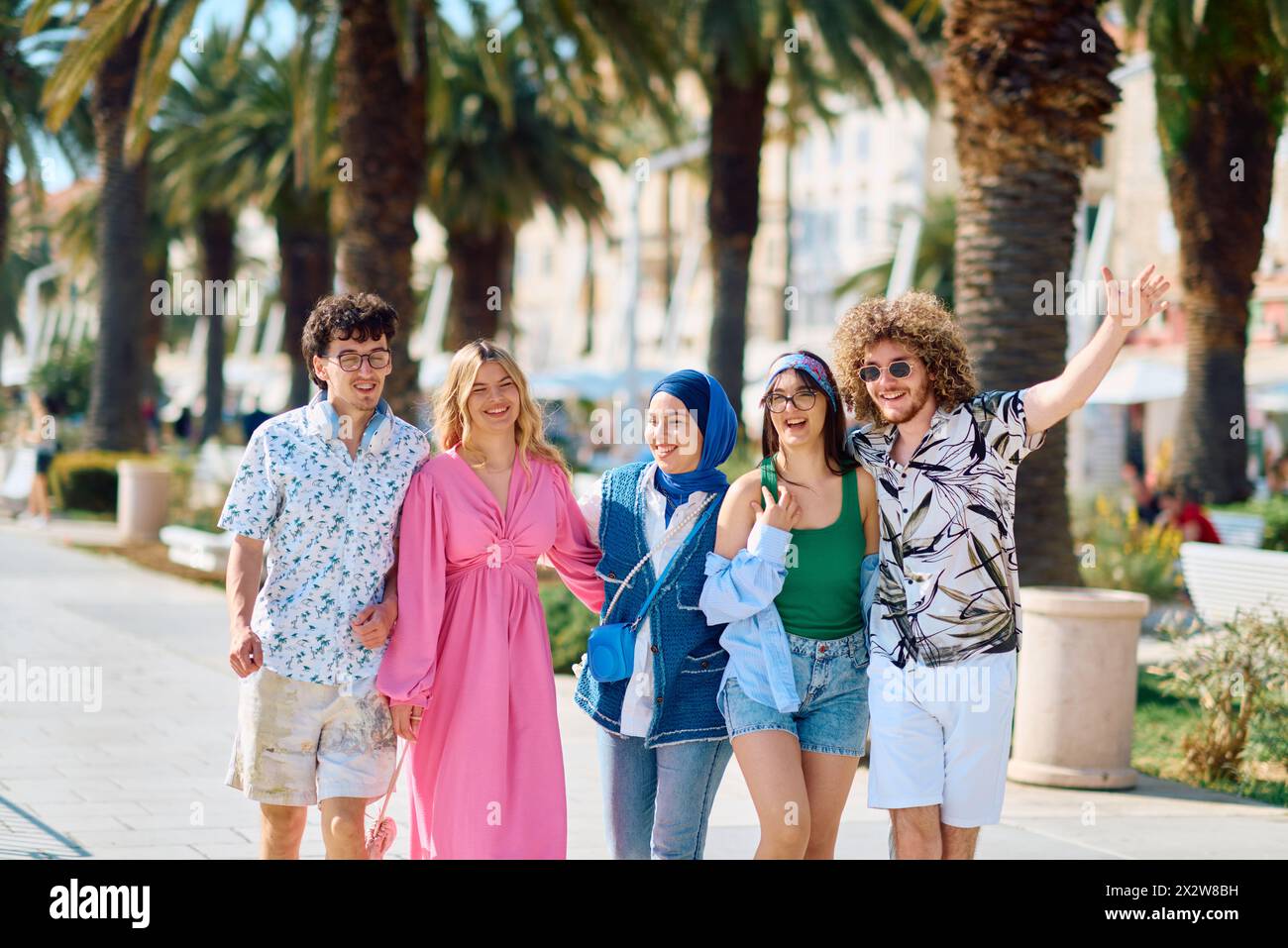 A diverse group of tourists, dressed in summer attire, strolls through ...