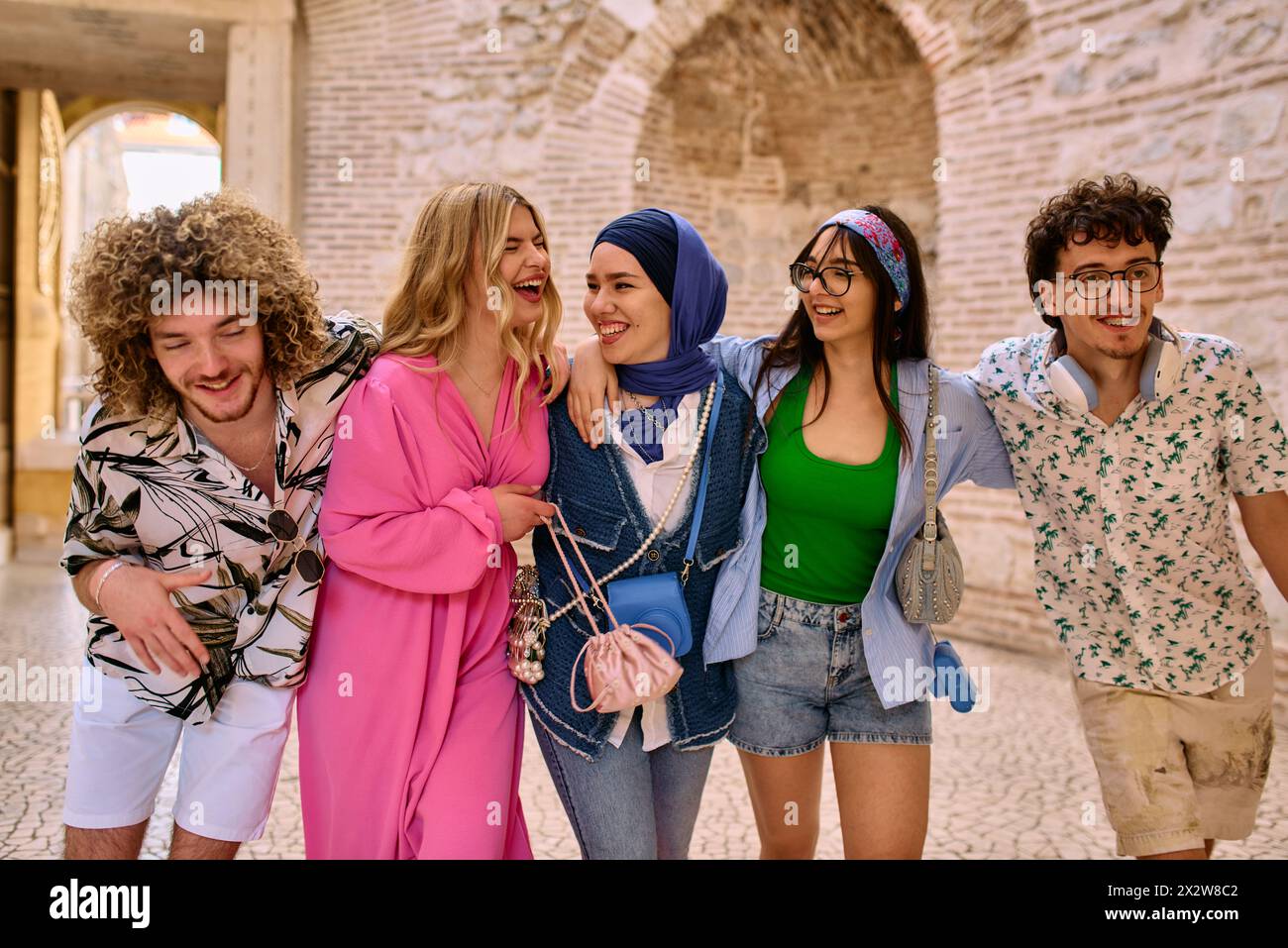 A diverse group of tourists, dressed in summer attire, strolls through ...