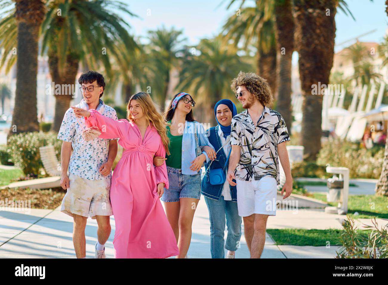 A diverse group of tourists, dressed in summer attire, strolls through ...