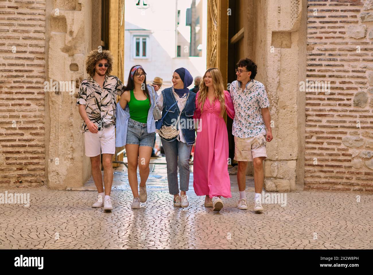 A diverse group of tourists, dressed in summer attire, strolls through ...