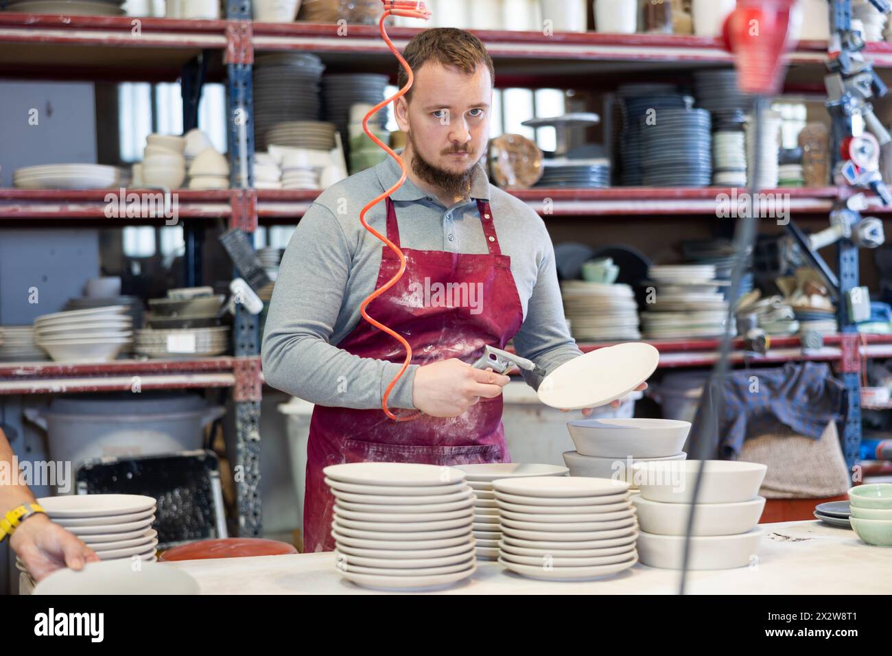 Potter removing dust from ceramics using air gun in workshop Stock ...