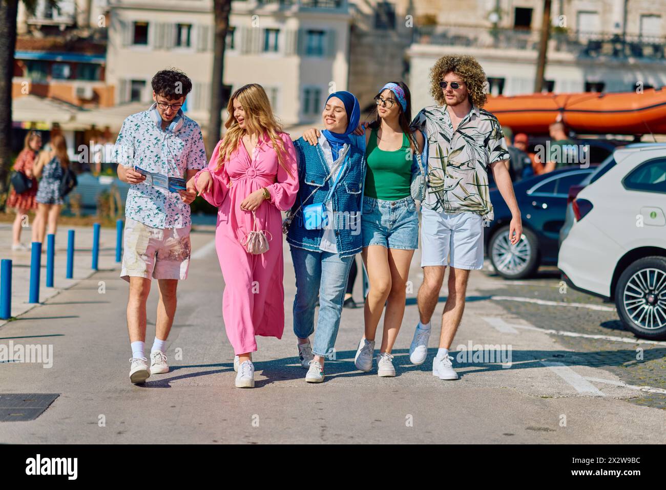 A diverse group of tourists, dressed in summer attire, strolls through ...