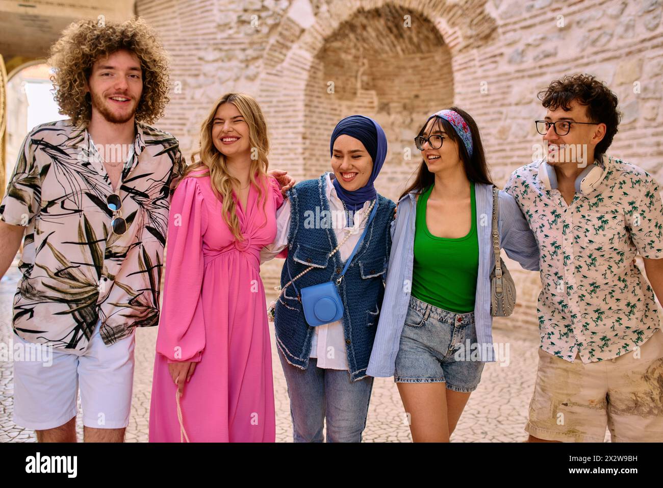 A diverse group of tourists, dressed in summer attire, strolls through ...