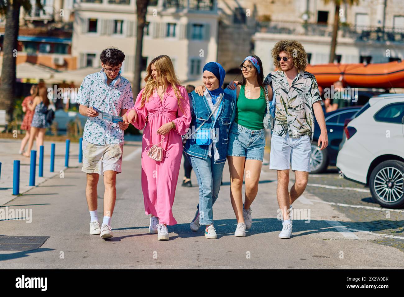 A diverse group of tourists, dressed in summer attire, strolls through ...