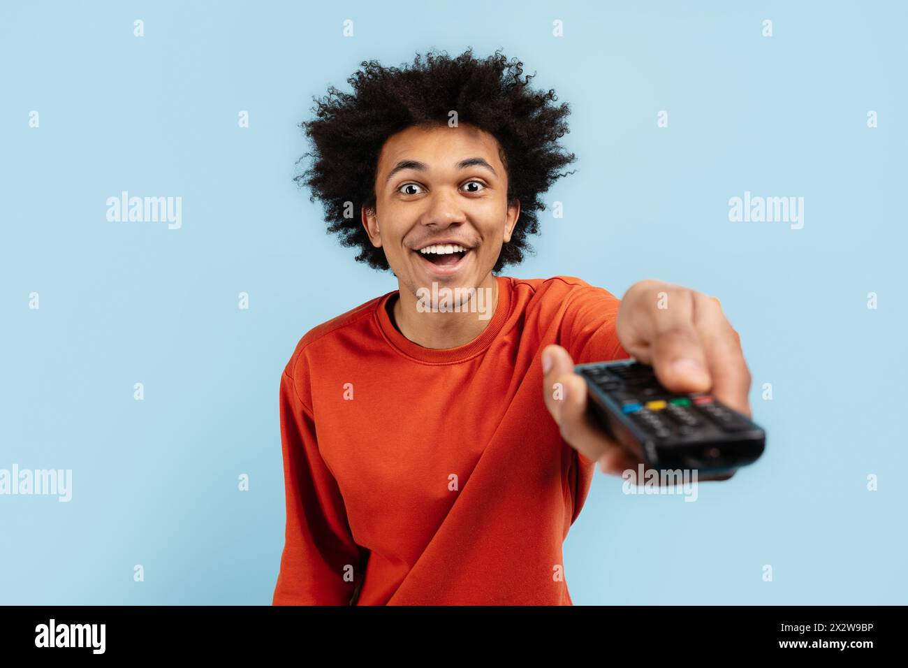 Excited black man with TV remote control Stock Photo - Alamy