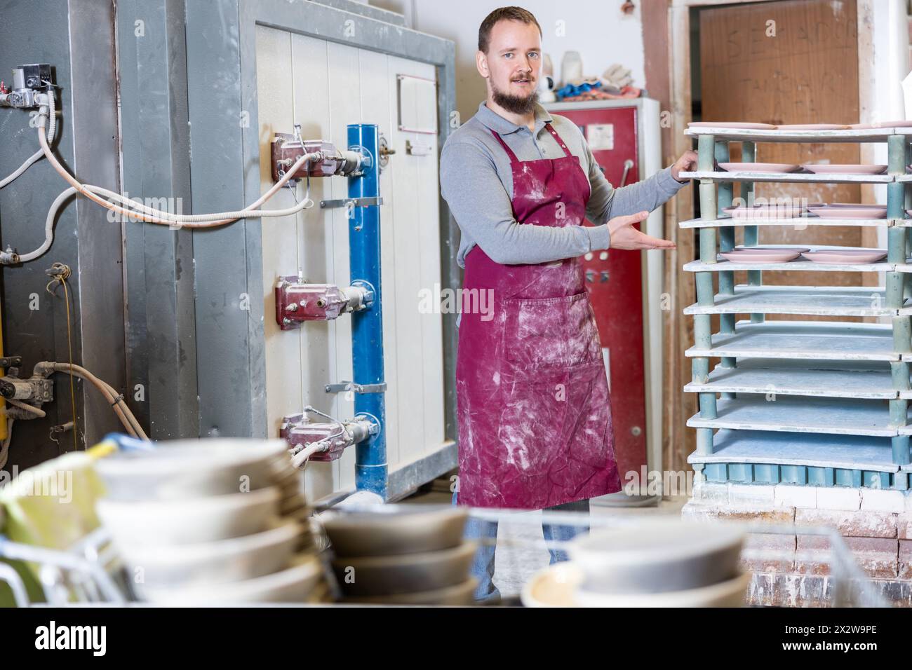 Young man posing at rack with ceramic dishes Stock Photo - Alamy