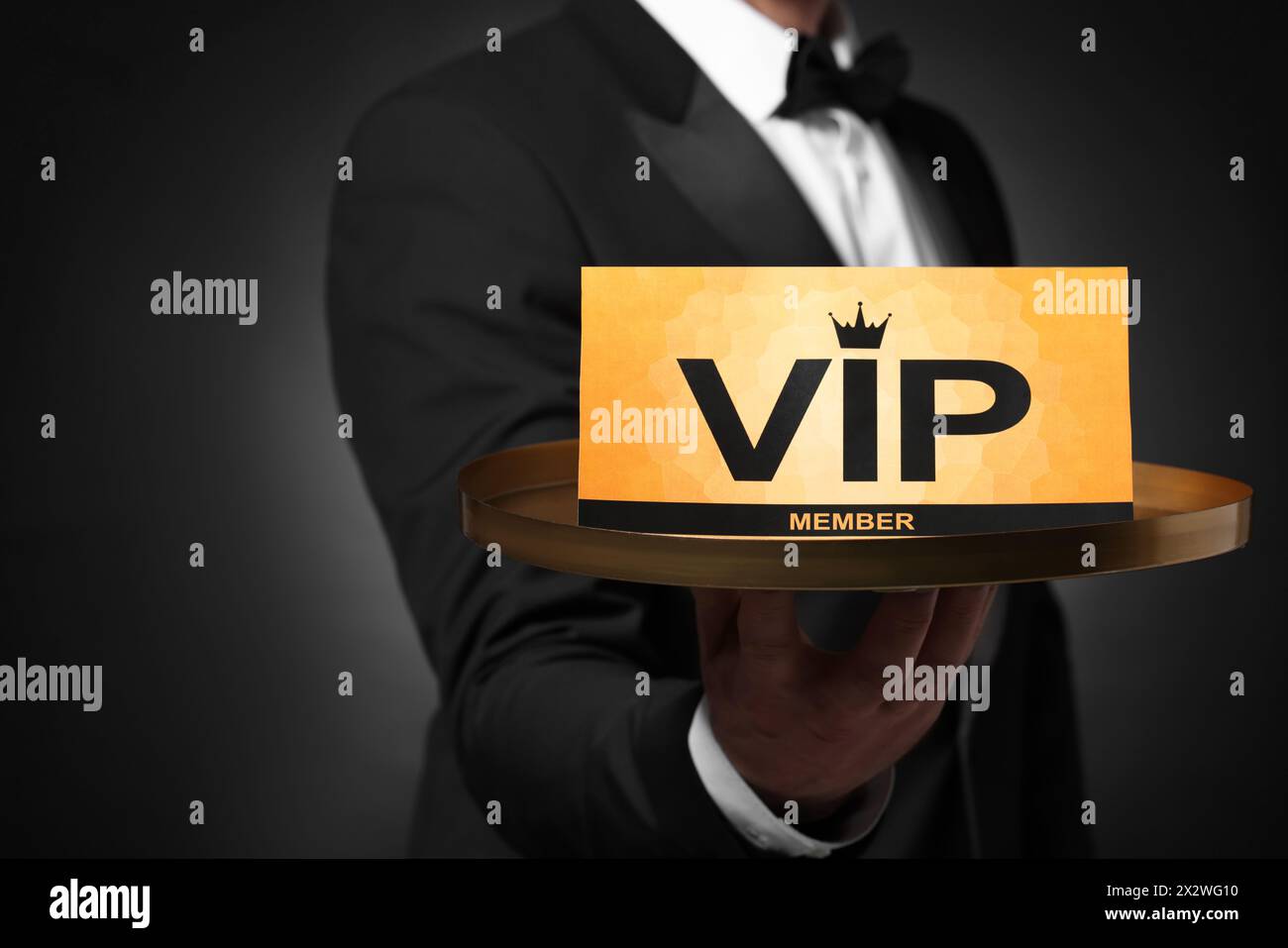 Man holding tray with VIP sign on black background, closeup. Space for ...