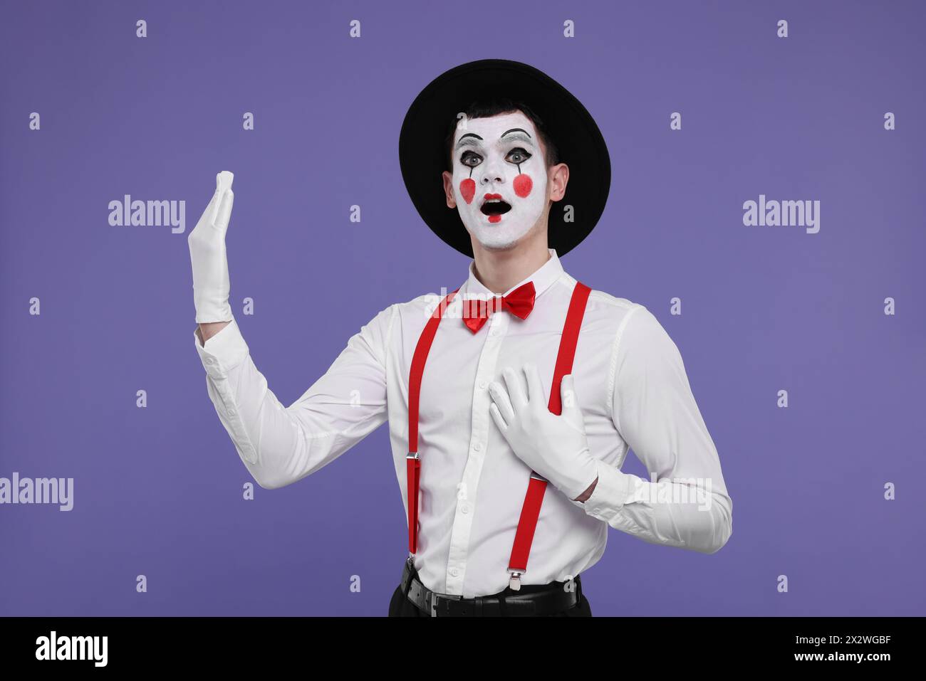 Mime artist making excited face on purple background Stock Photo - Alamy