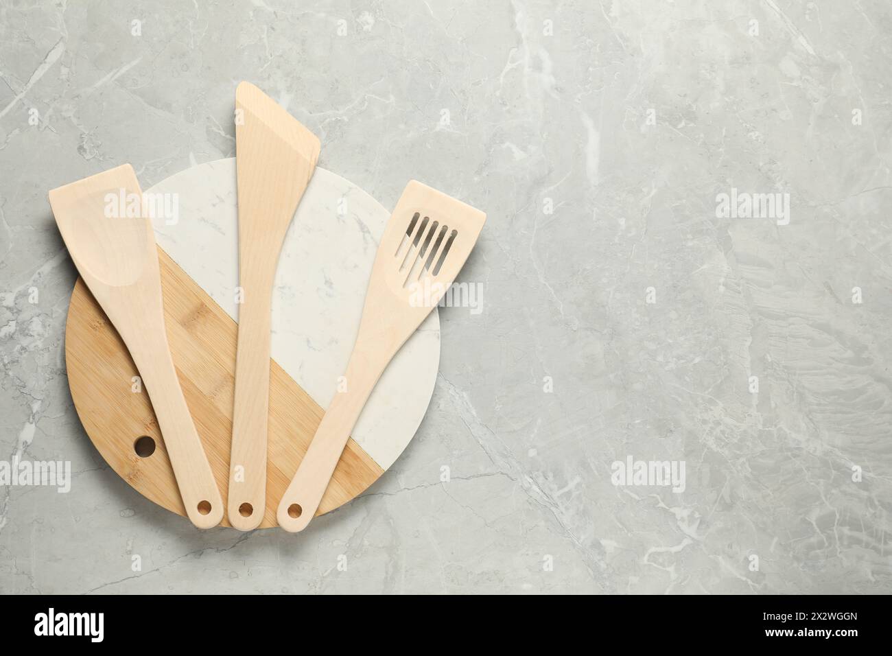 Different wooden spatulas and board on grey textured table, top view ...