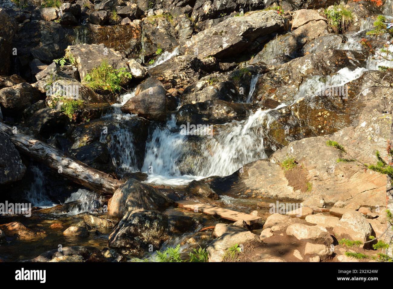 A stormy river flows down from the mountains in a cascade of waterfalls ...