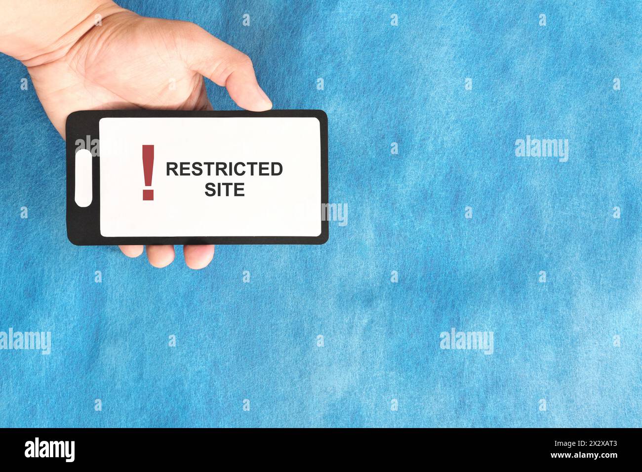Hand holding a mobile phone with Restricted Site and Website Blocked ...