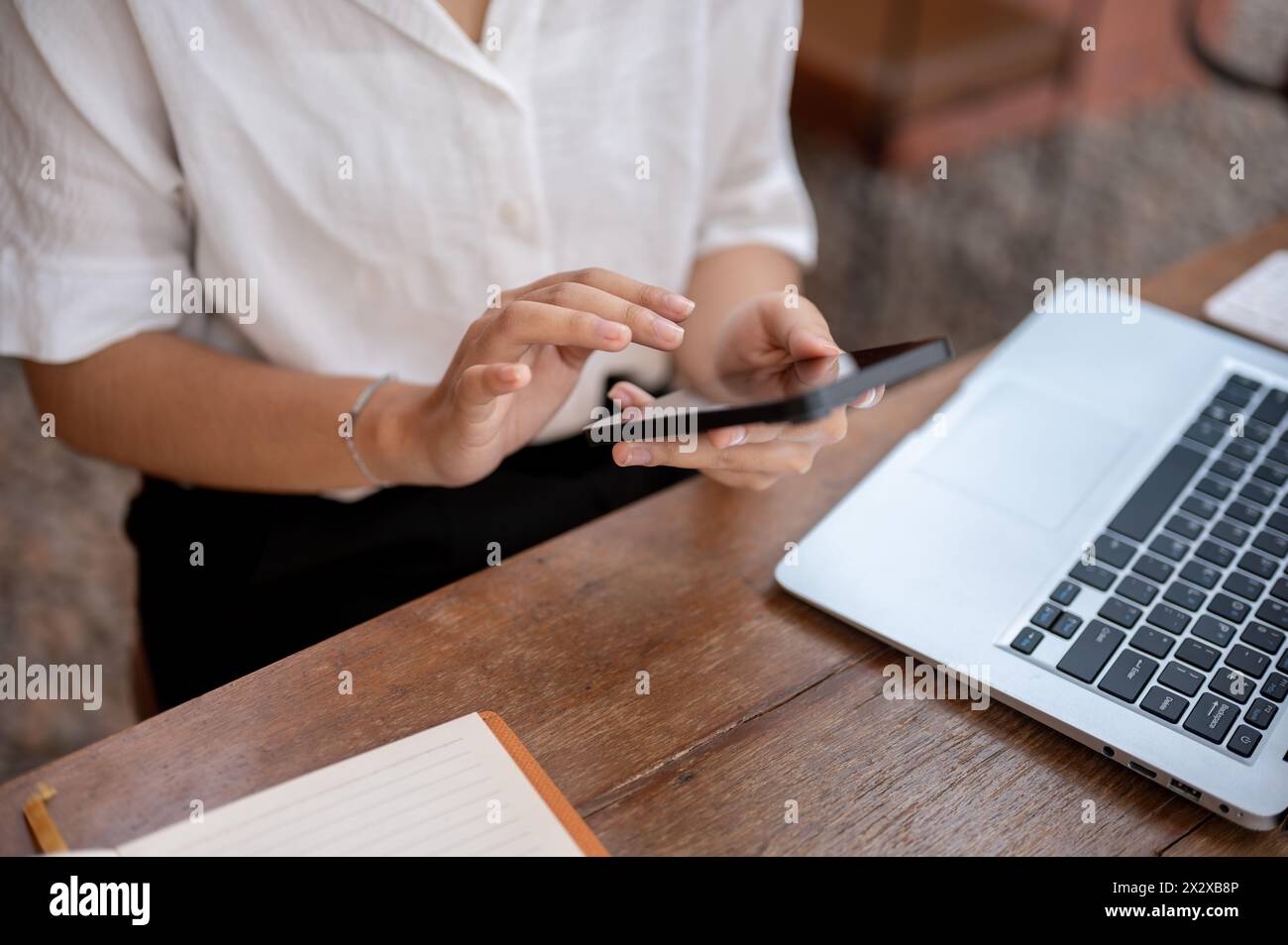 A close-up cropped image of a woman using her smartphone, touching on ...