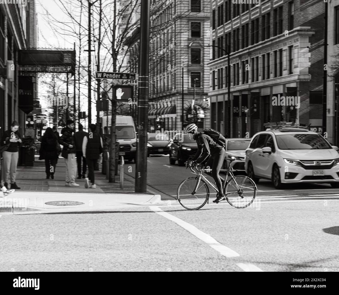 A black and white photo of a bicycle rider crossing Howe Street at the ...