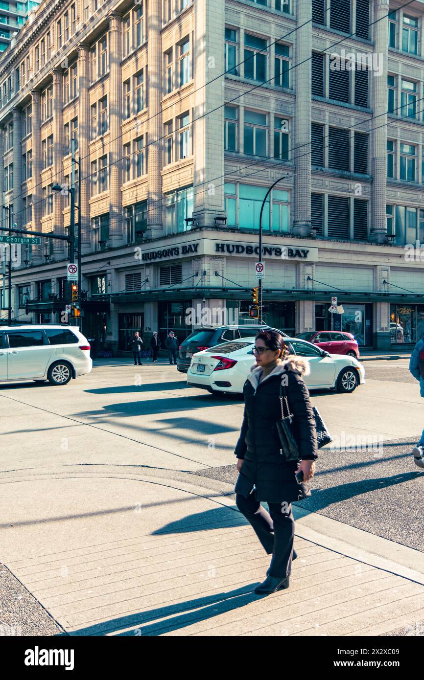 A pedestrian crossing Granville Street at the intersection with Georgia Street, with the Hudson ...