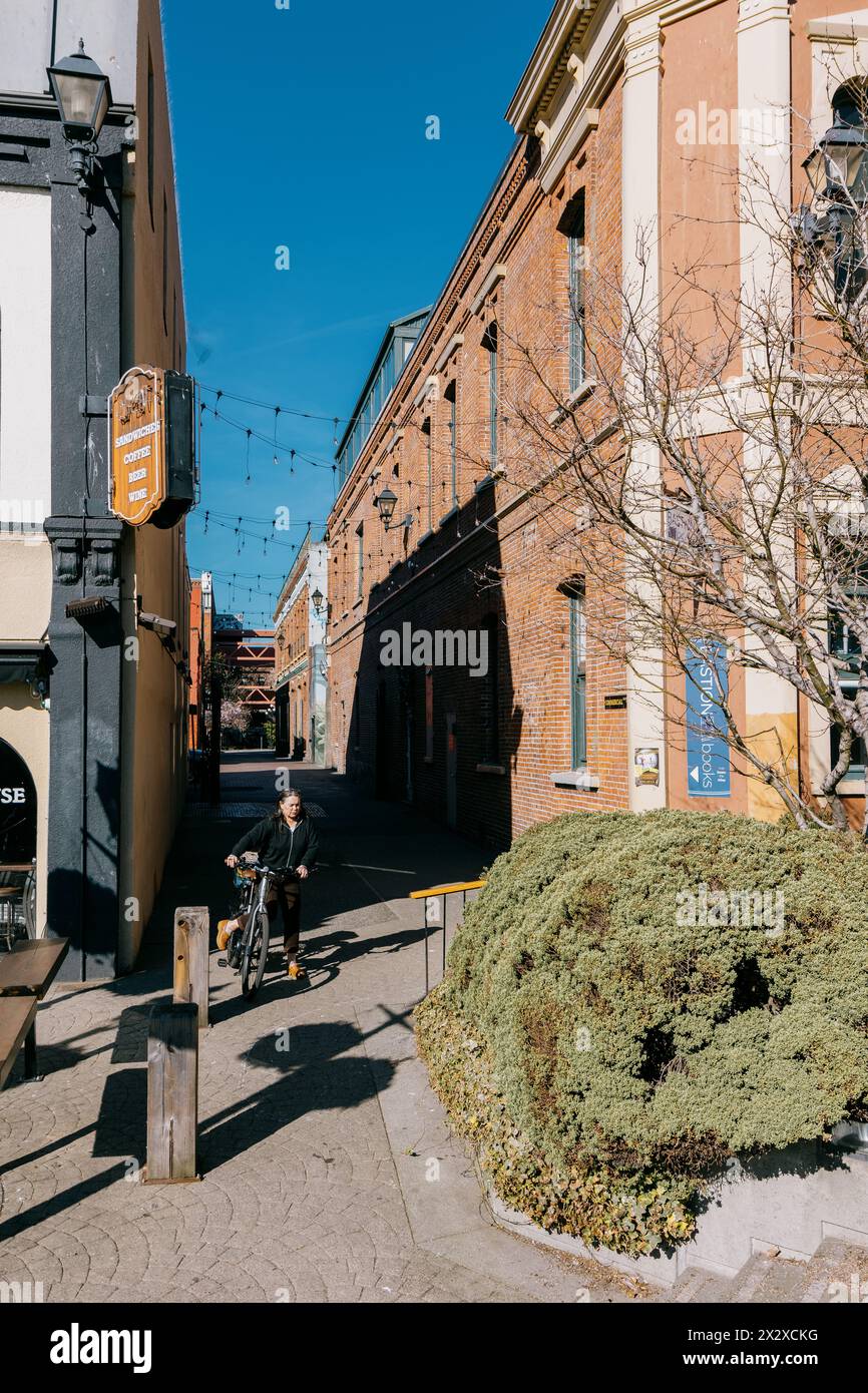 Victoria, Canada - Mar 18 2024: A woman getting off her bicycle at the ...