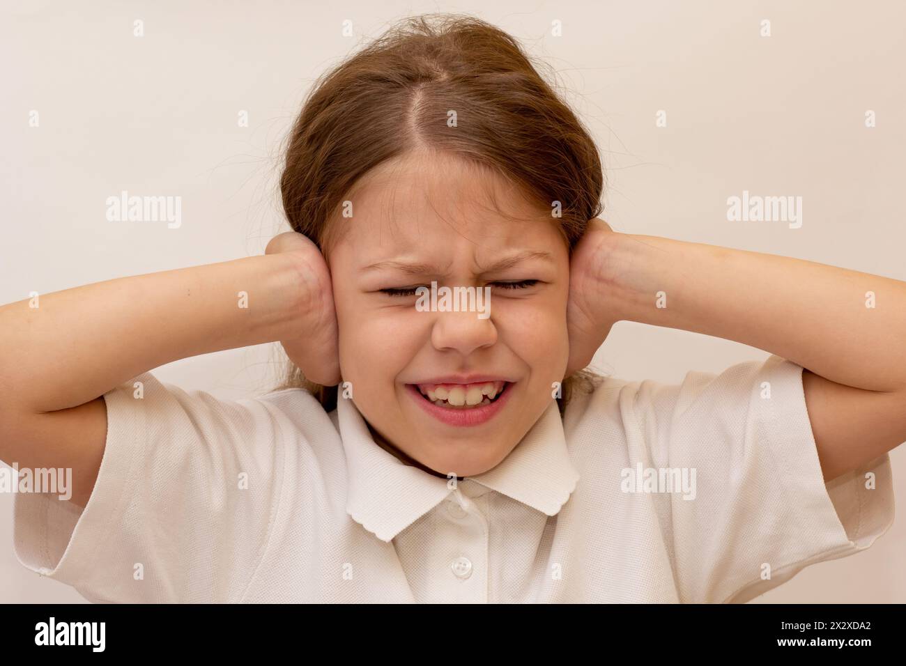 Portrait of caucasian child close ears by hands on white background ...