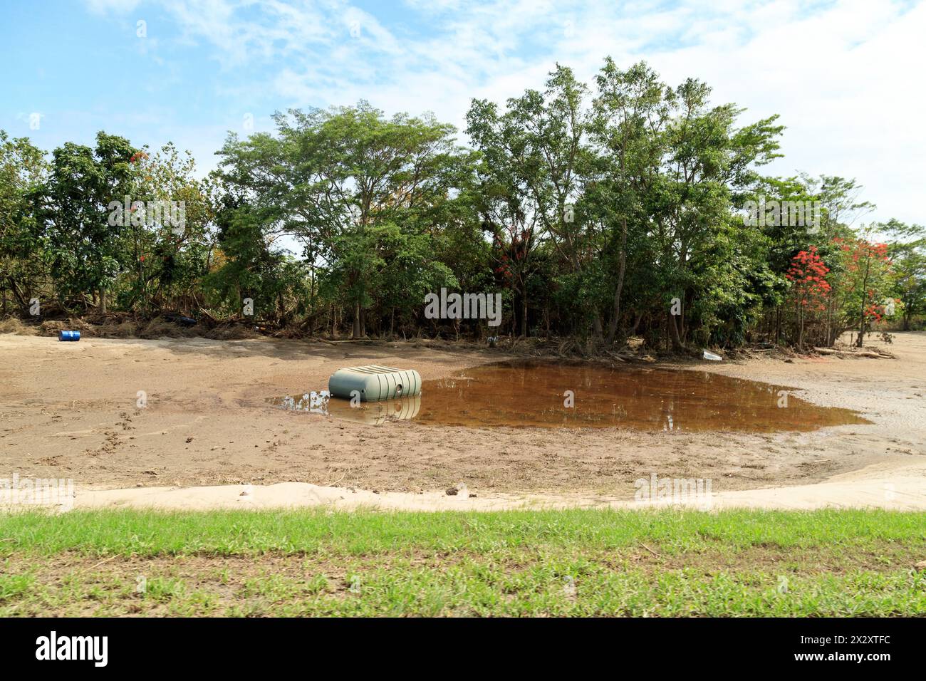 A water tank carried by major flooding remains in the mud near Thomatis Creek north of Cairns ...