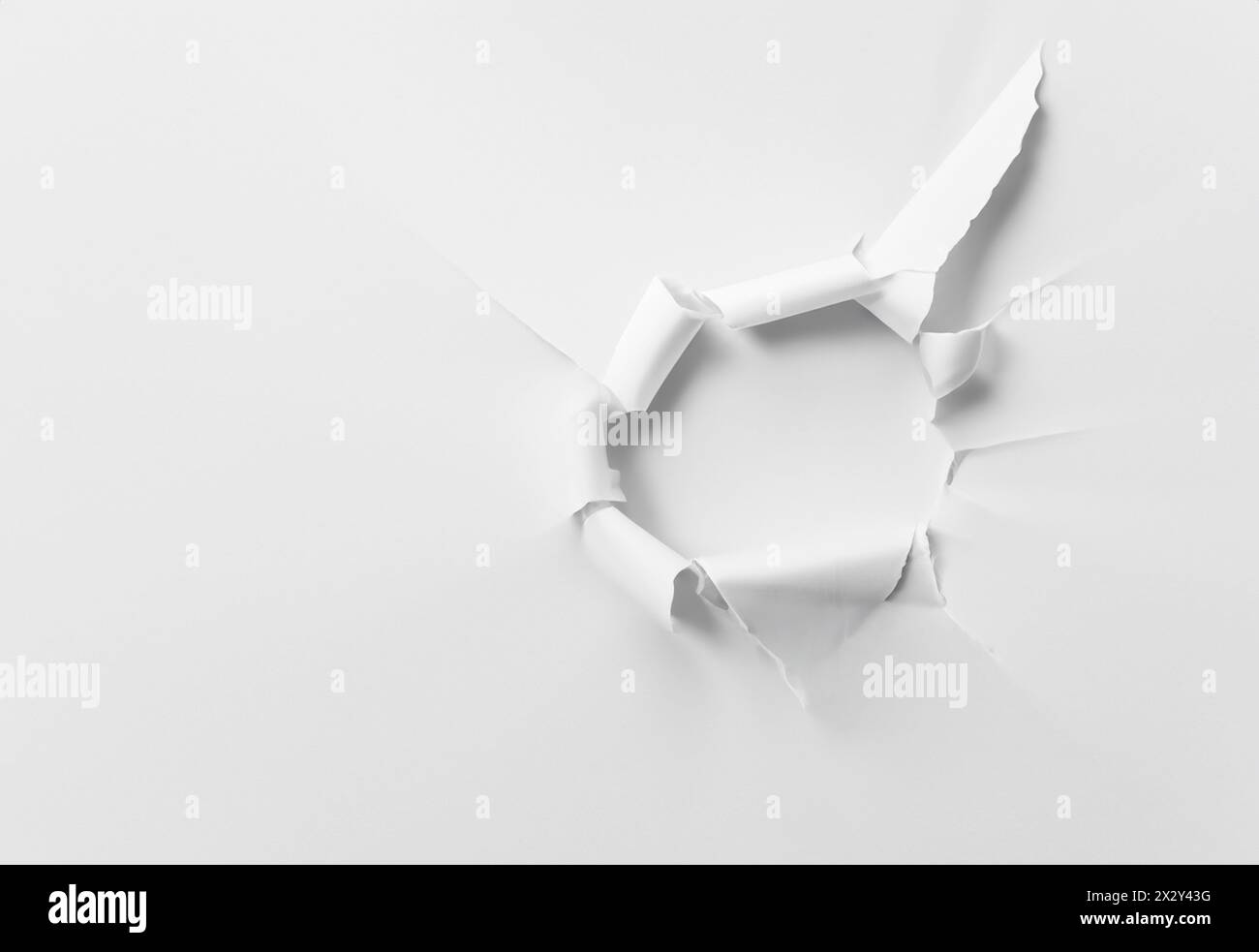 Round opening resembling a bullet hole with curled edges in a sheet of ...