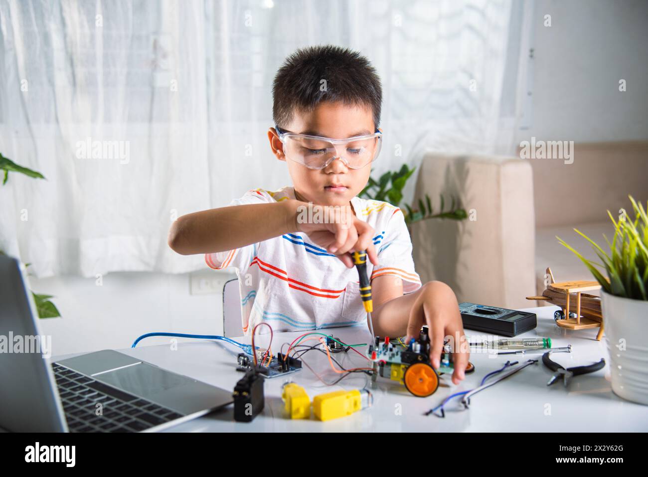 Asian kid boy assembling the Arduino robot car homework project at home ...