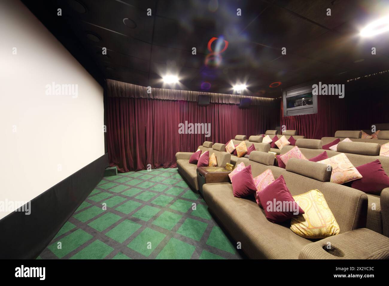 Screen and soft sofas with cushions in small hall of cinema theatre ...