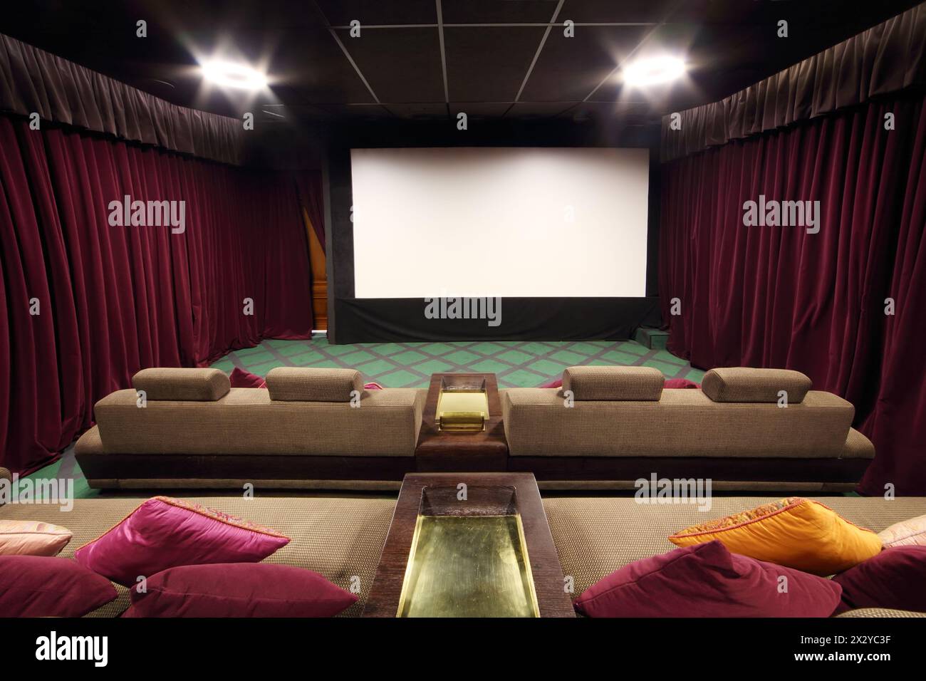 Back of soft couches with pillows and white screen in small hall of ...