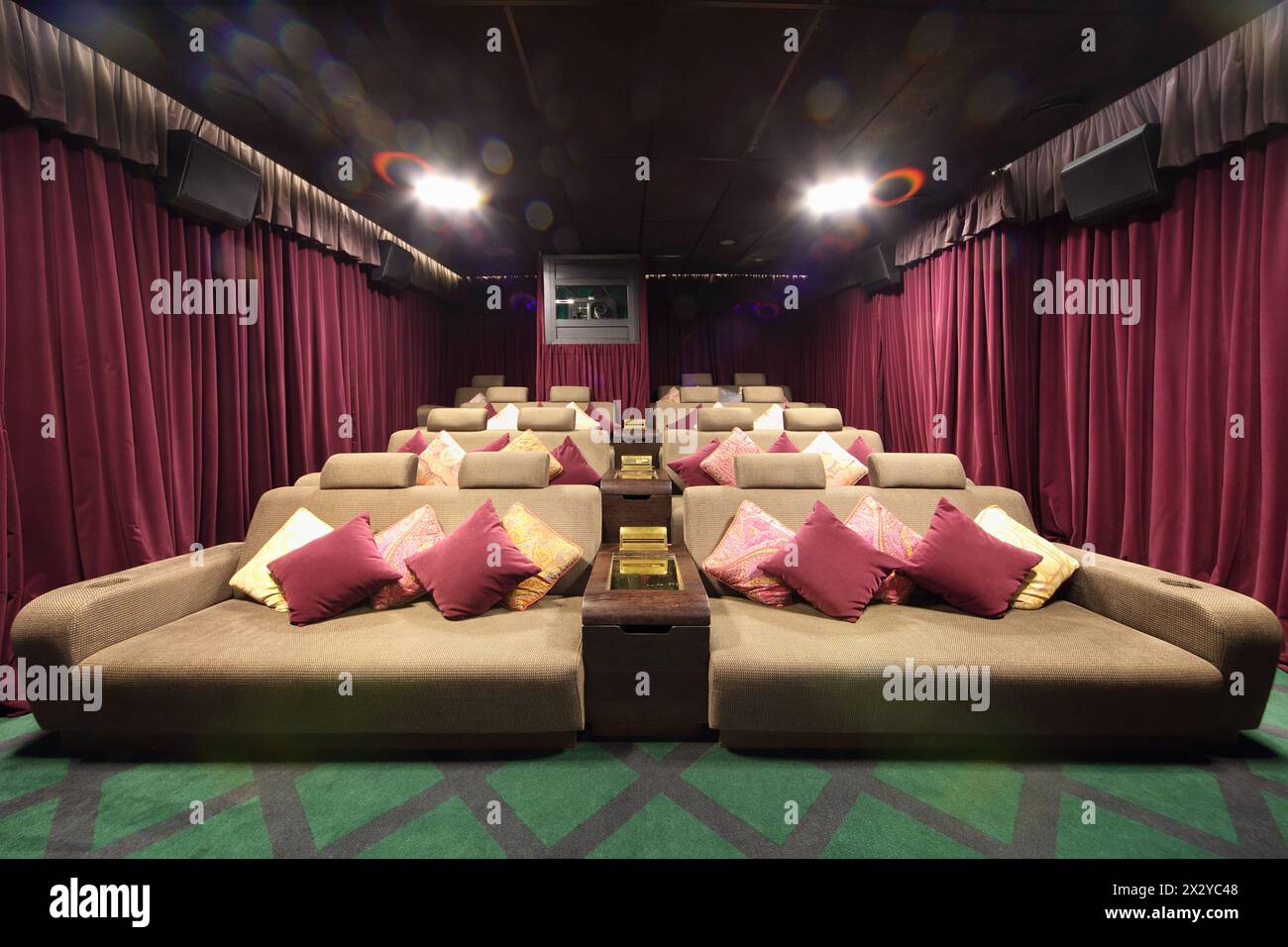 Small hall of cinema with soft couches with pillows and red curtains ...
