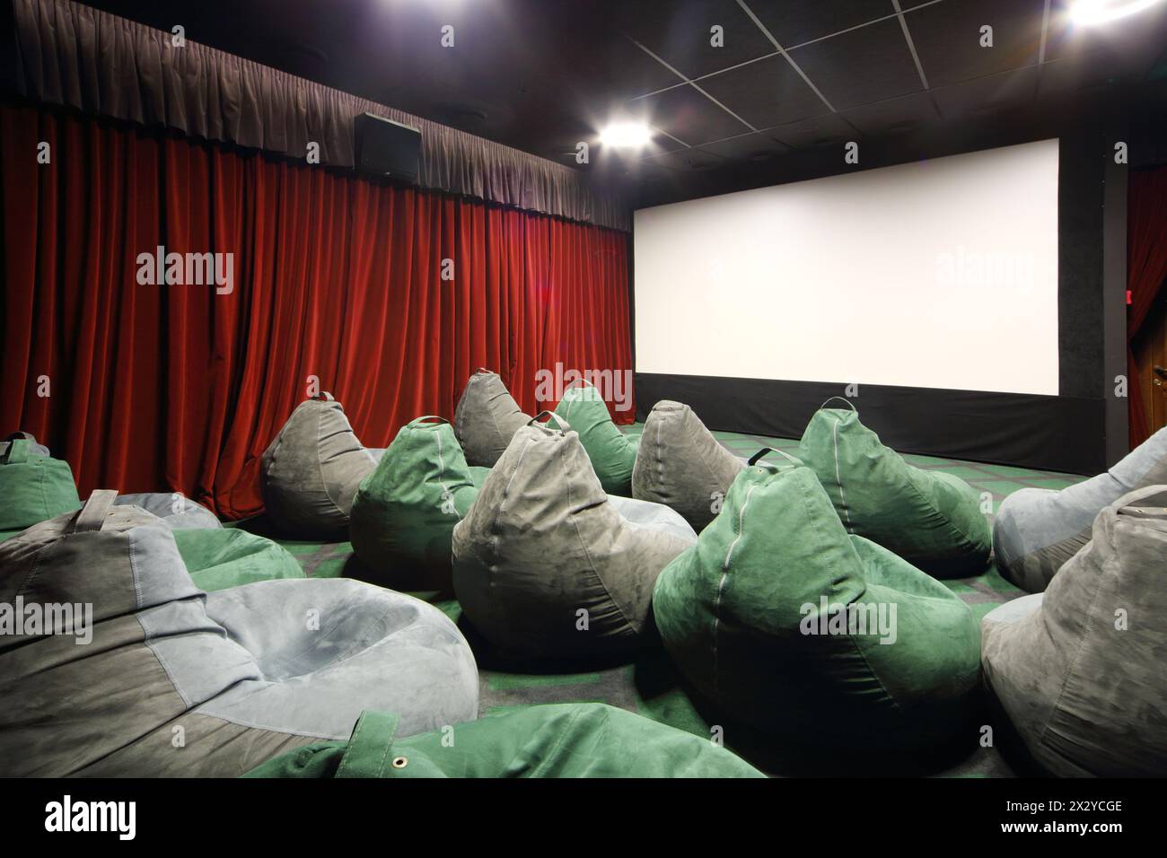 Back of comfortable seats like sacks and white screen in small movie ...