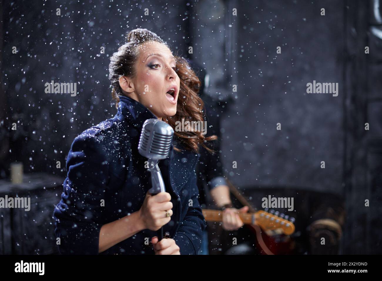 Young female vocalist sings into microphone during shooting video clip ...