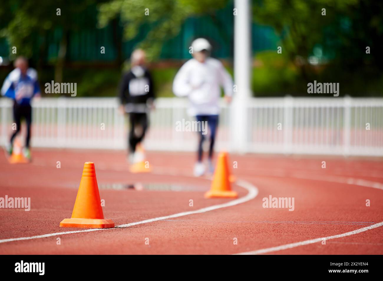 Running track at stadium with runners, focus on cone Stock Photo - Alamy