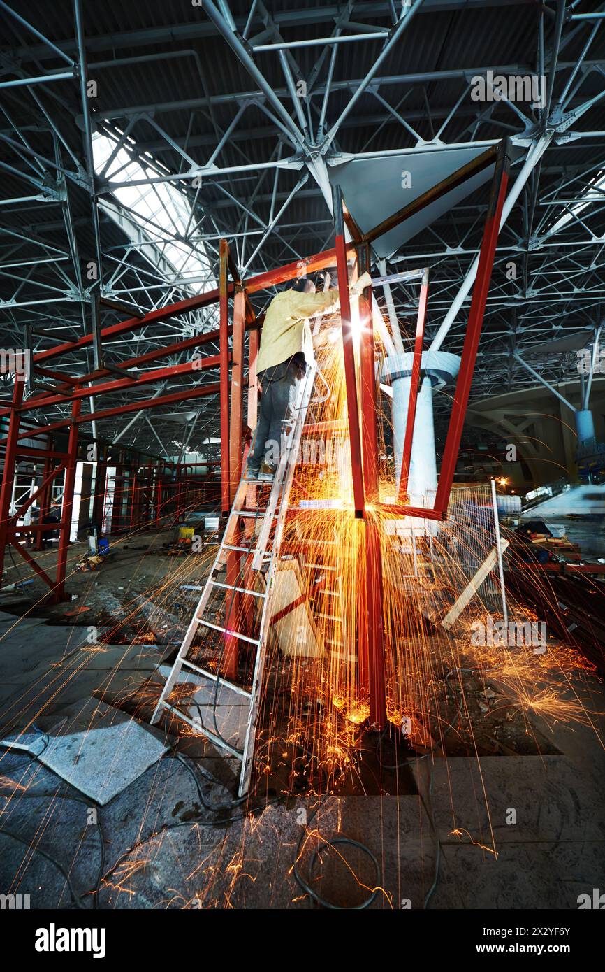 Welder welds steel frame standing on stepladder Stock Photo - Alamy