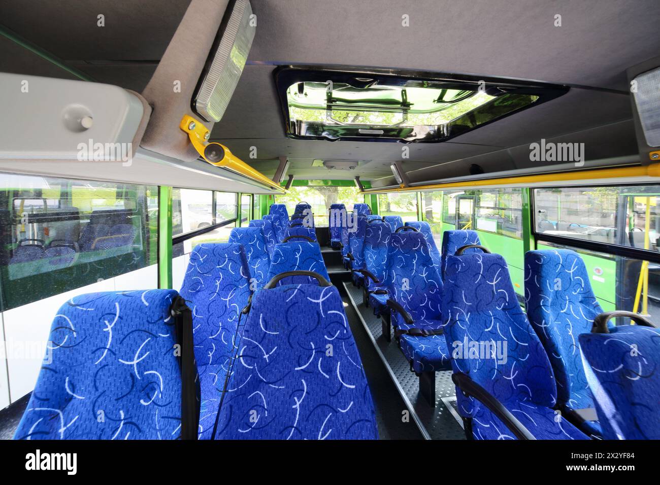 Rows of soft blue seats inside saloon of empty city bus with skylight ...