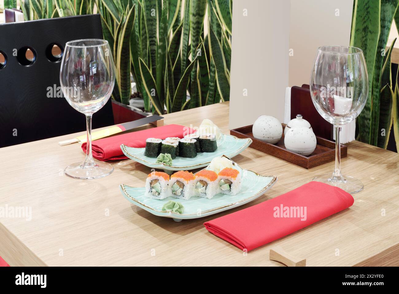 Table with sushi at plates and empty glasses in small modern Japanese ...