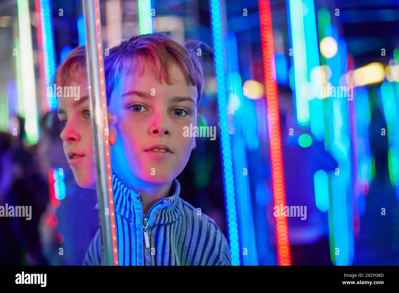 Boy stands in mirror labyrinth illuminated with color lights Stock ...